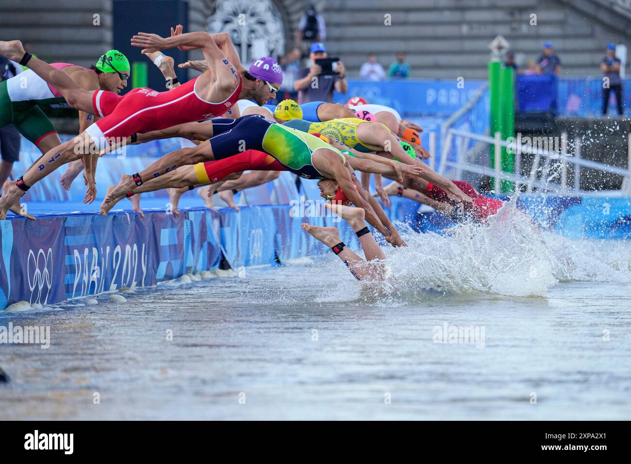 Athletes dive into the water for the start of the mixed relay triathlon ...
