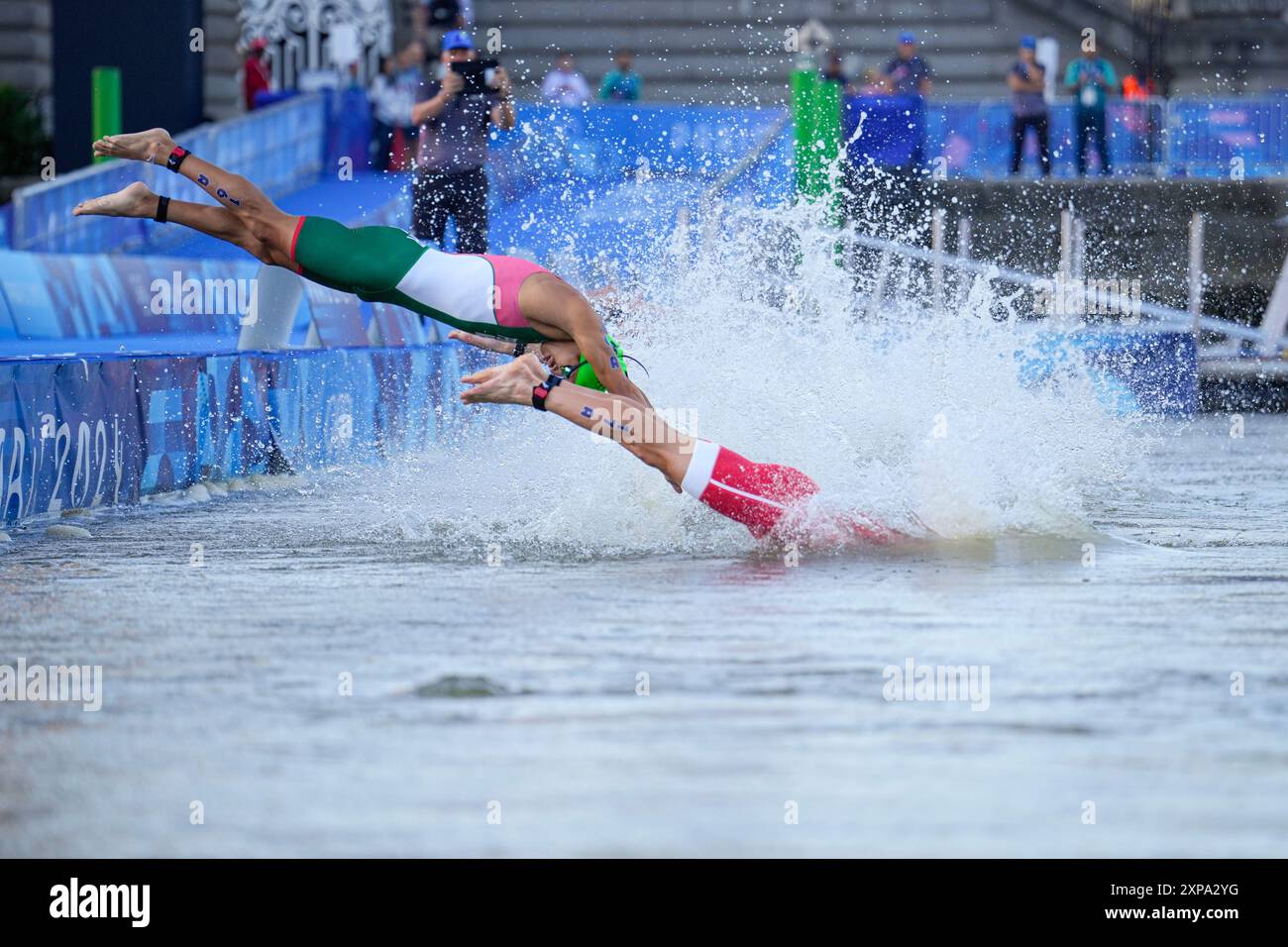 Athletes dive into the water for the start of the mixed relay triathlon ...