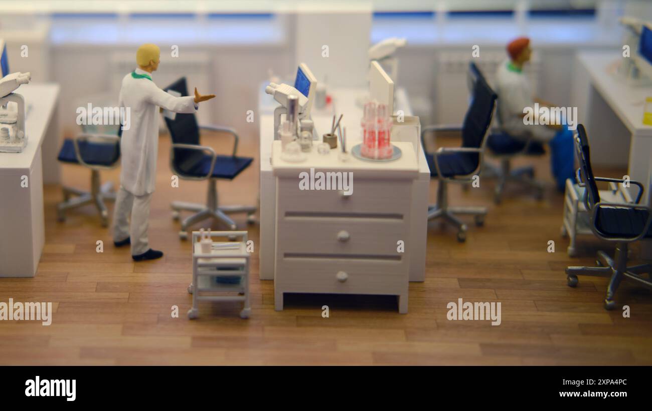Miniature figures of scientists working in a modern laboratory with ...