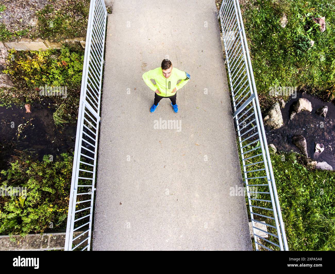 Aerial view of a runner standing on bridge in park, resting. Morning ...