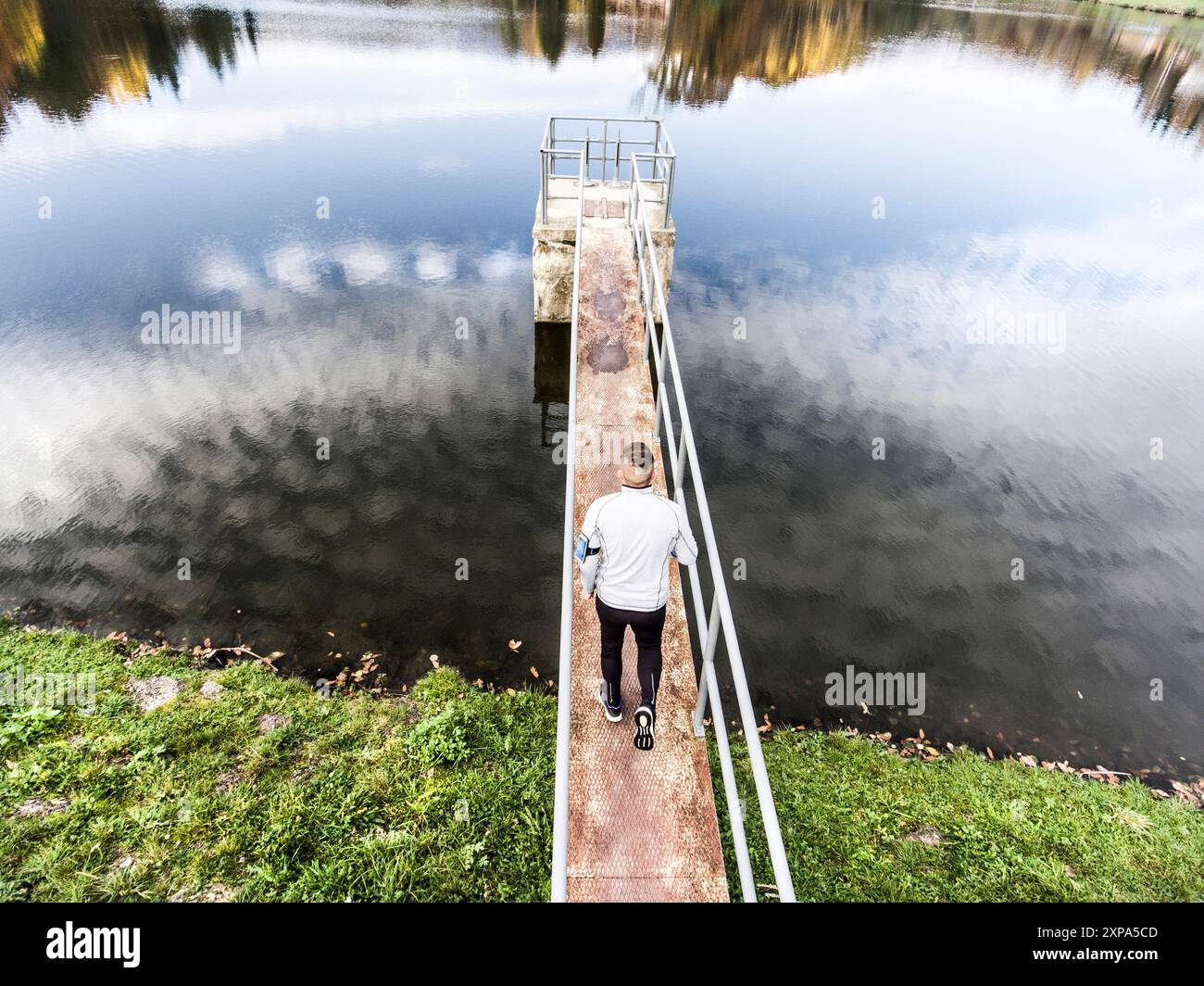 Aerial view of a runner running across bridge in park on a jogging path ...