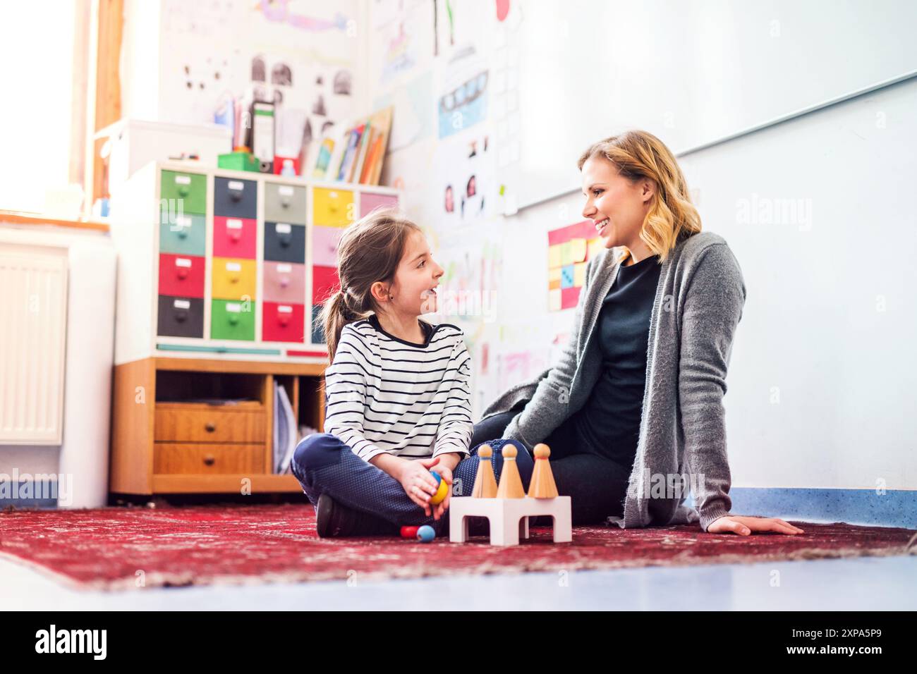 Hardworking teacher learning with young schoolgirl in classroom ...