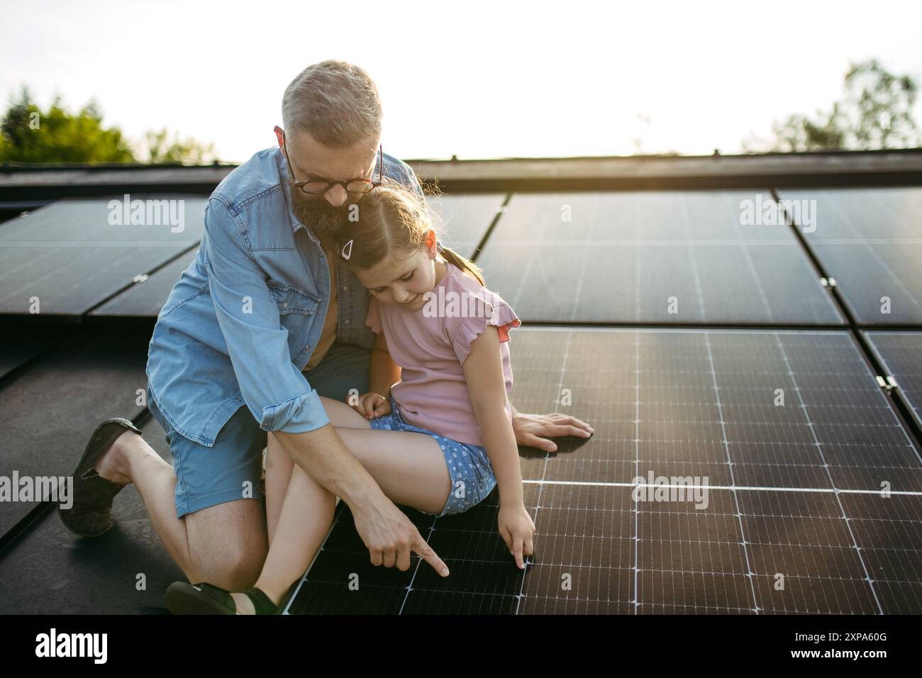 Dad and girl on roof with solar panels, learning about solar energy ...