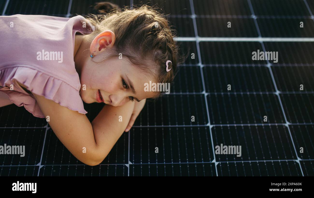 Cute girl lying on solar panels roof, shot with copy space. Rooftop ...