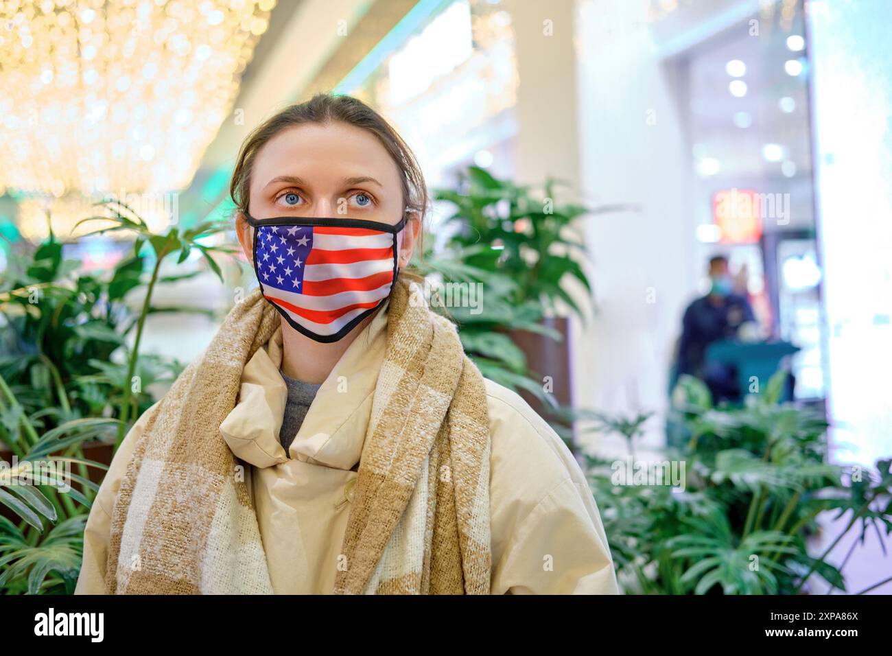 Woman wearing American flag face mask and beige scarf standing in ...
