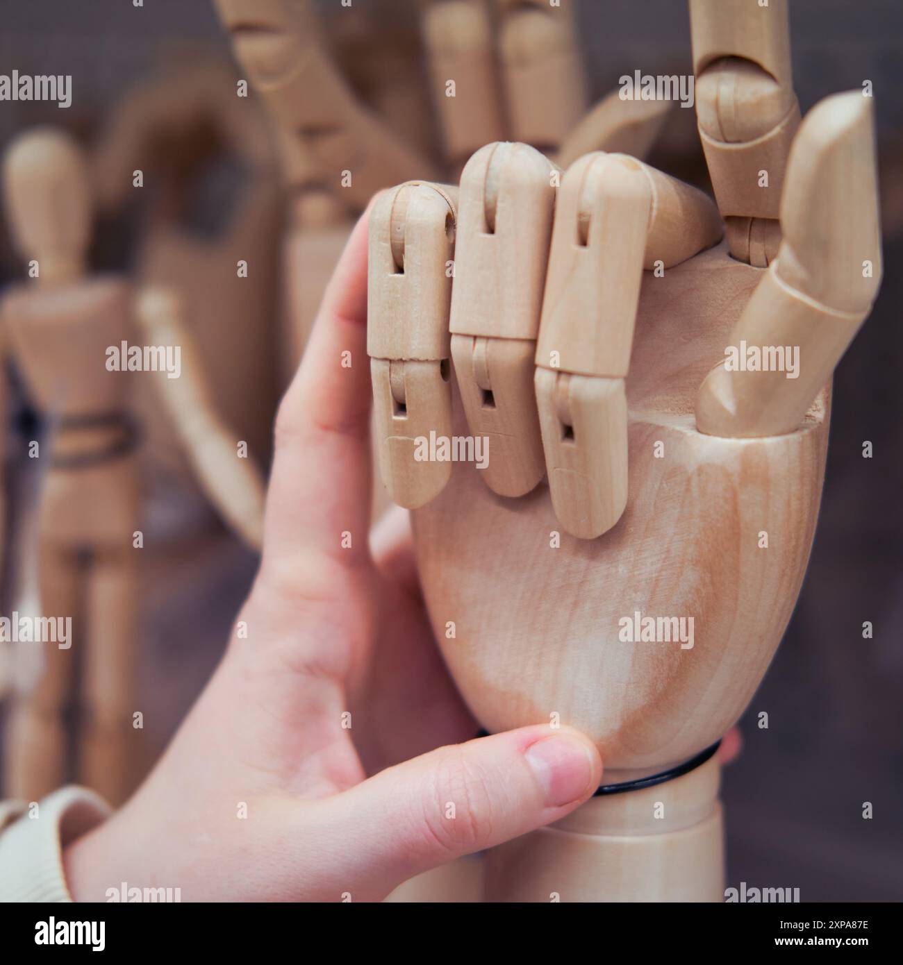 Hand holding a wooden artist mannequin hand. Close-up photography for ...