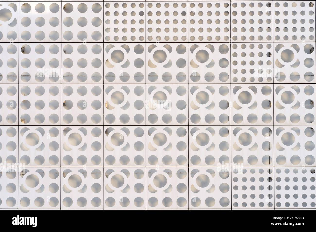 Grid of white metal panels with circular cutouts creating geometric ...