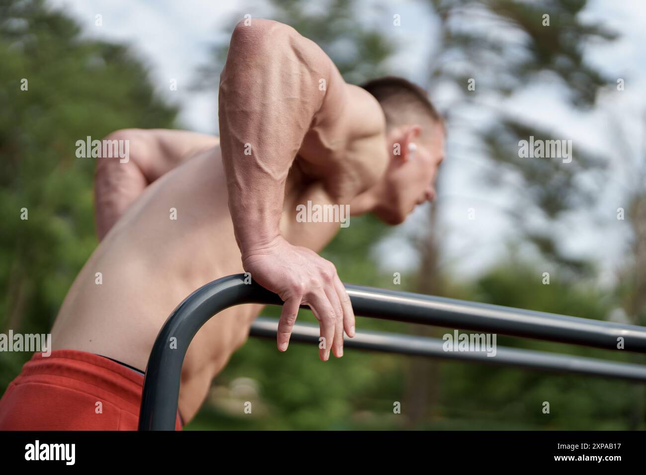 Focused athlete doing outdoor dip exercise on parallel bars Stock Photo ...