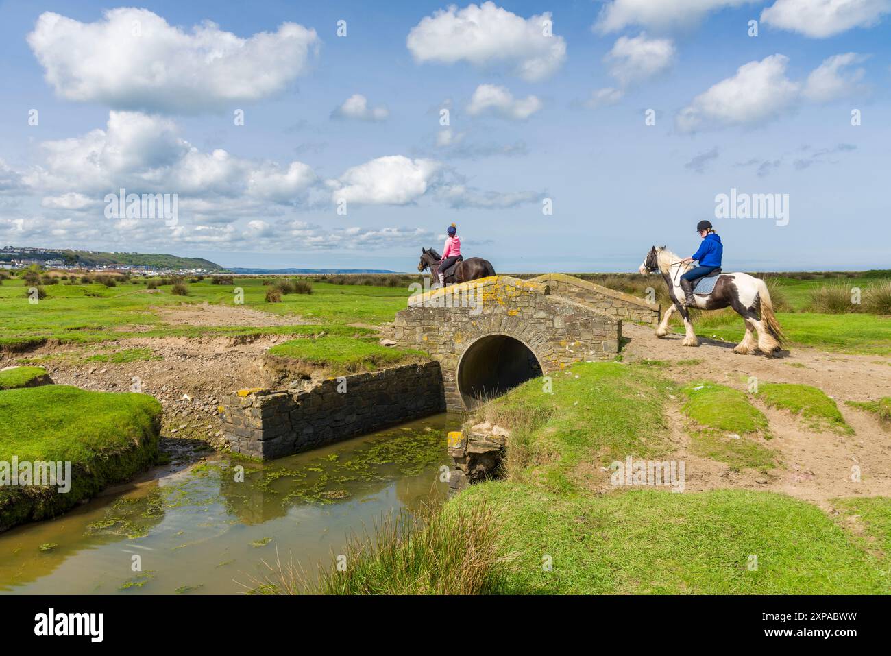 Two horse riders crossing a bridge over The Pill in the Northam Burrows ...