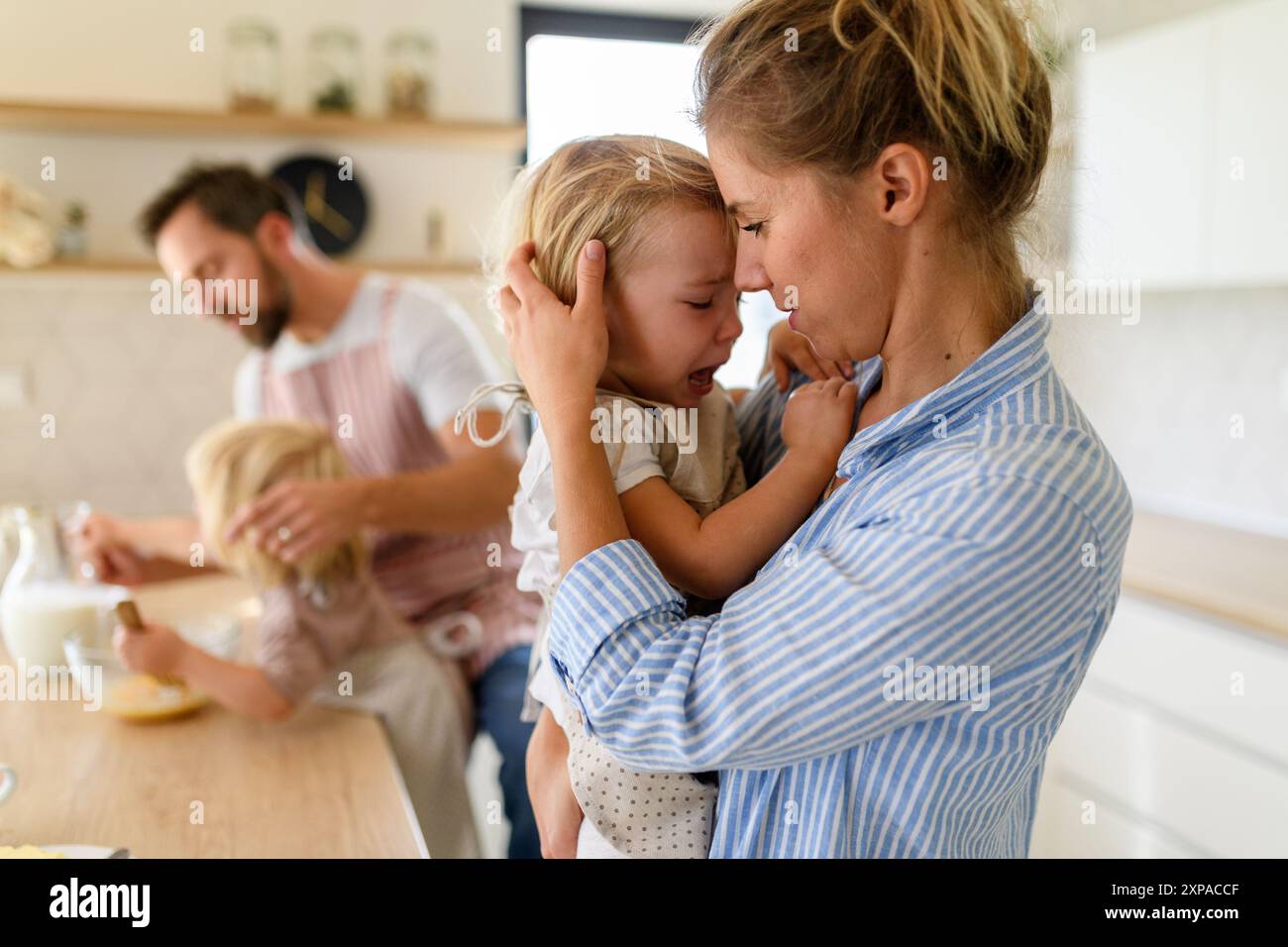 Little girl crying and screaming, mother holding her in arms and ...