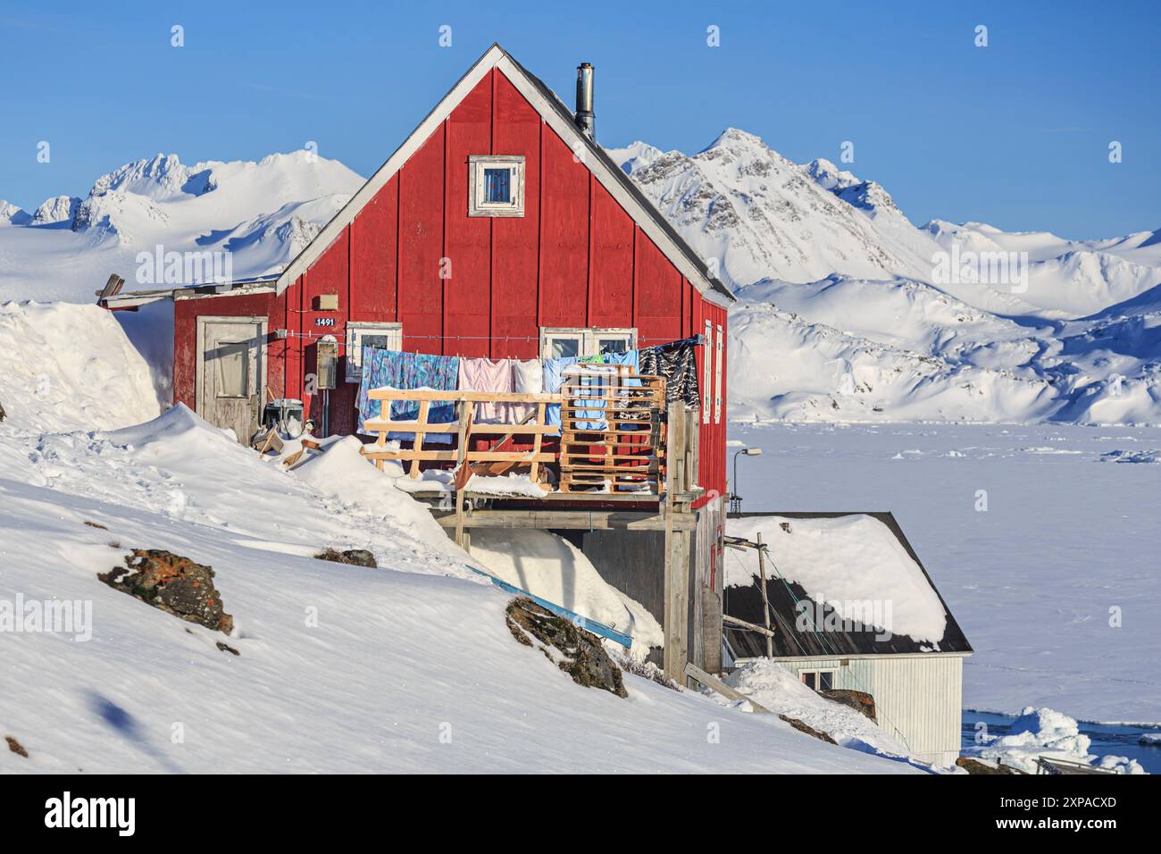 Typical greenlandic house in front of icebergs and mountains, winter ...