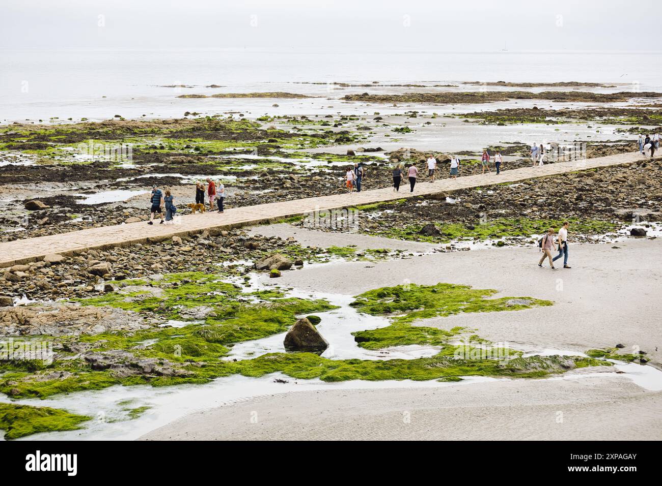 Tourists walking the granite causeway from Marazion to tidal island of ...