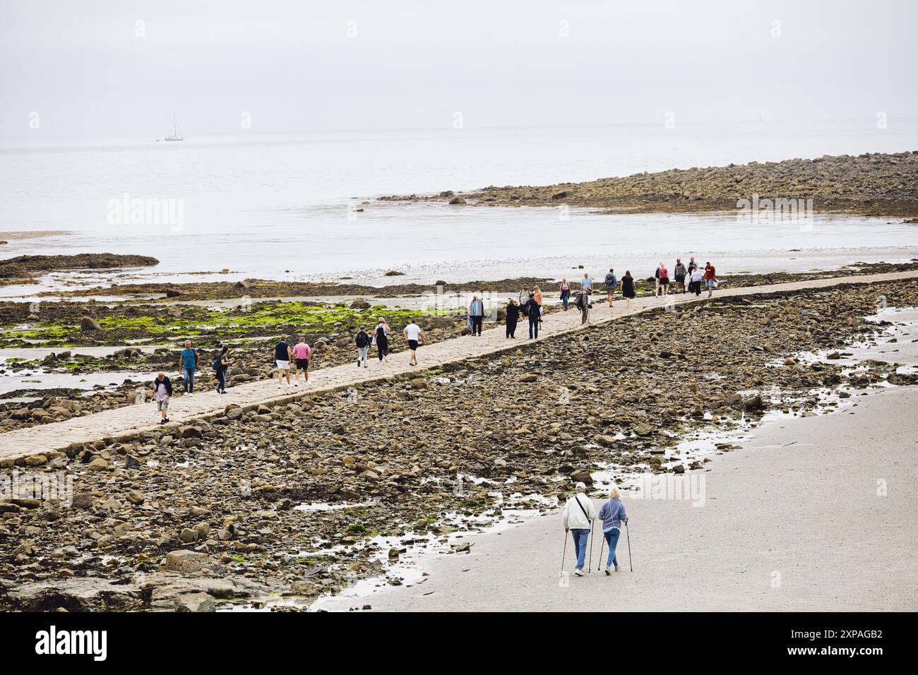 Tourists walking the granite causeway from Marazion to tidal island of ...