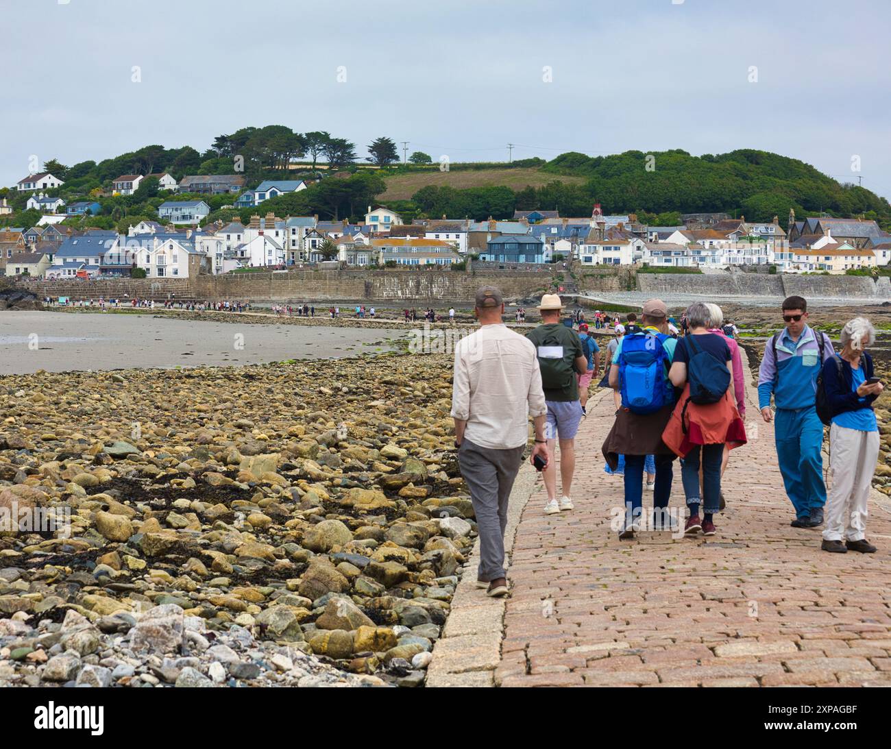 Tourists walking the granite causeway from Marazion to tidal island of ...
