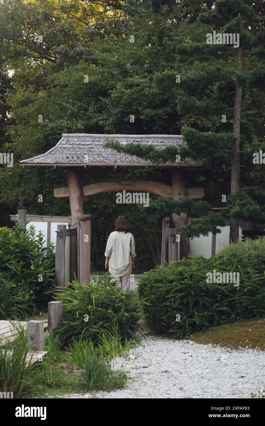 Person walking through a traditional Japanese garden gate with lush ...