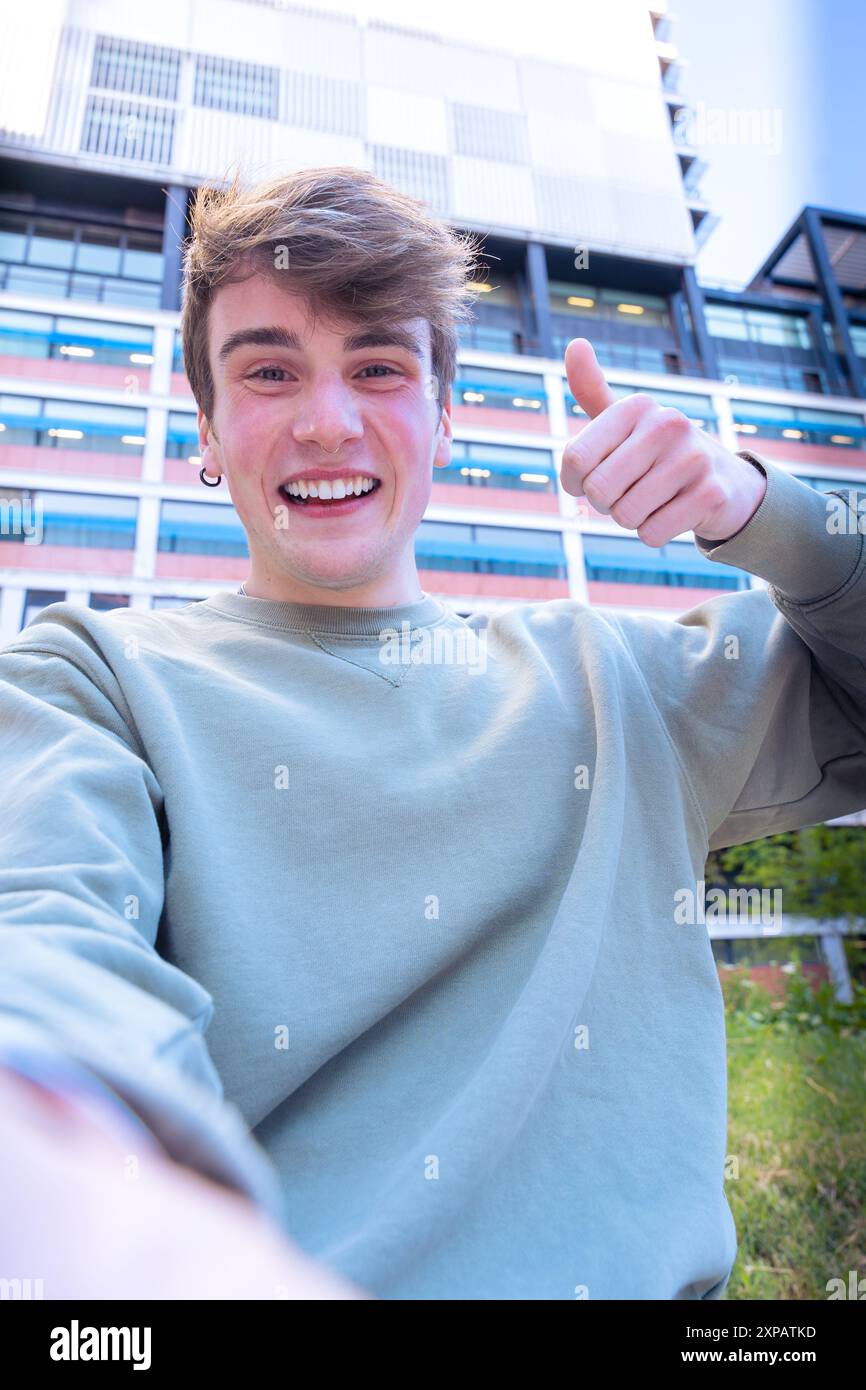 A smiling young man with a smartphone saying hello on a video call ...