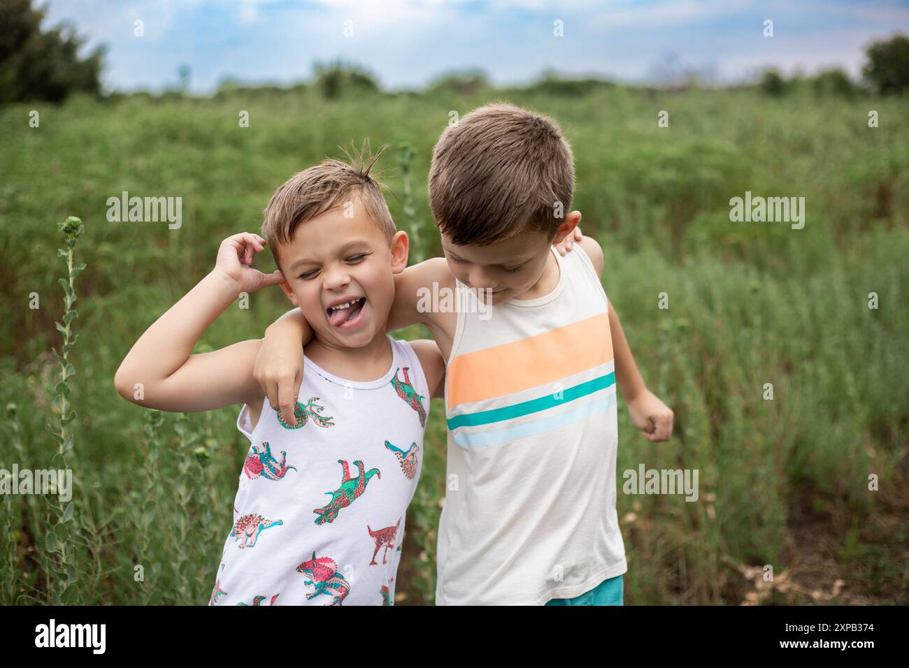 two boys in green field smiling and making goofy face Stock Photo - Alamy