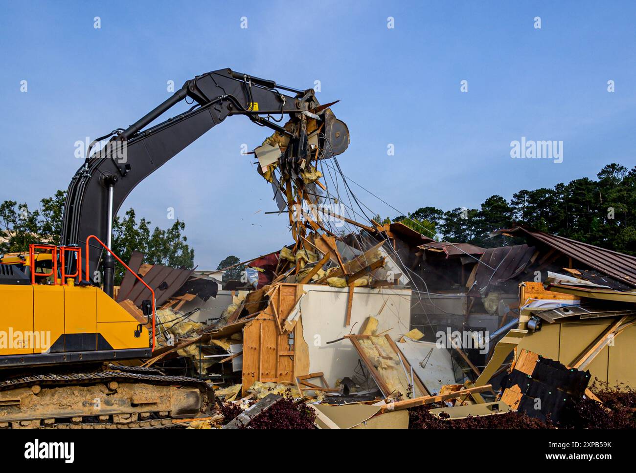 A large excavator machine tears down a defunct building Stock Photo - Alamy