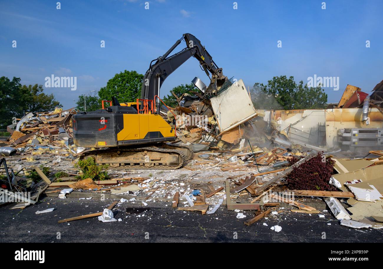 A large excavator machine tears down a defunct building Stock Photo - Alamy