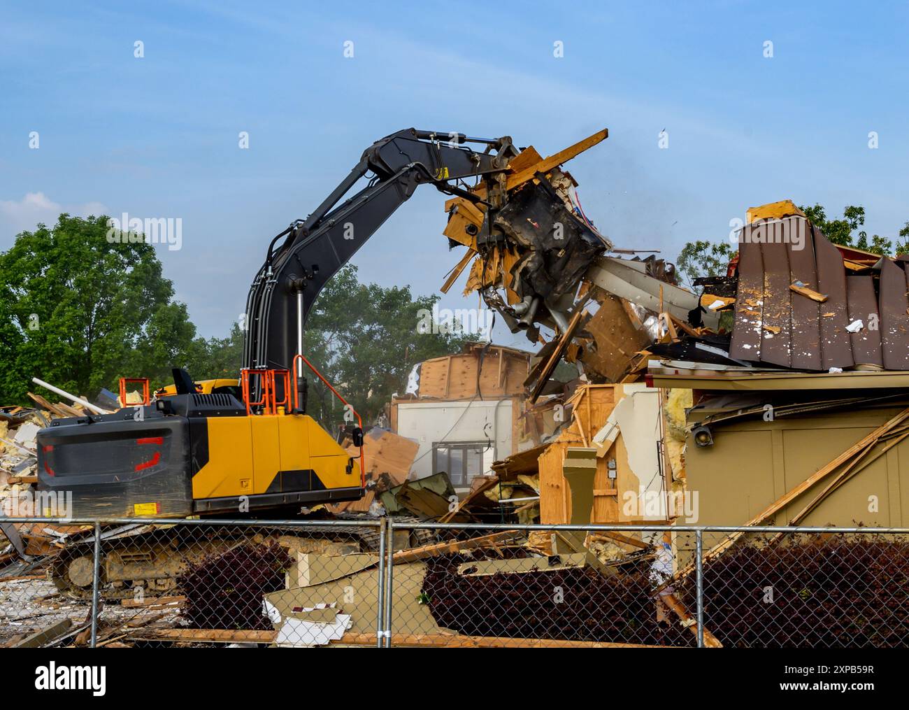 A large excavator machine tears down a defunct building Stock Photo - Alamy
