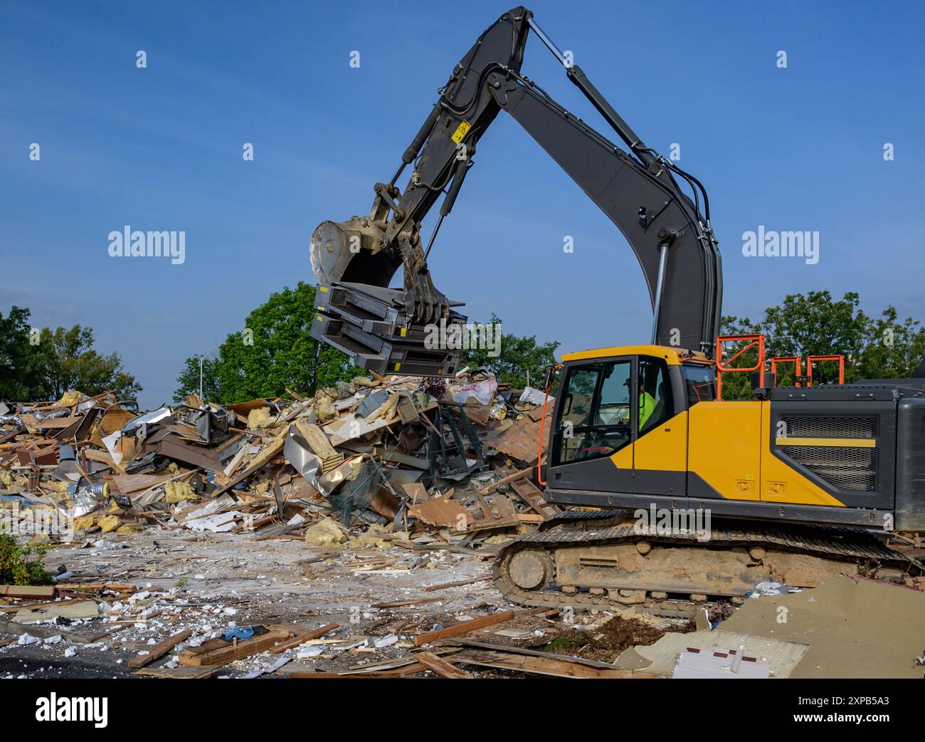 A large excavator machine tears down a defunct building Stock Photo - Alamy