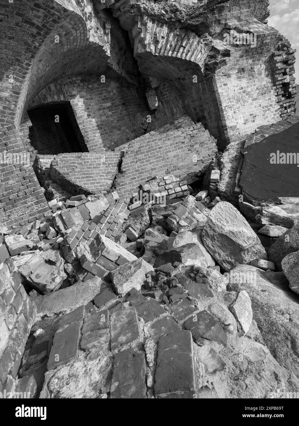 Black and white image of collapsed brick building ruins surrounded by ...