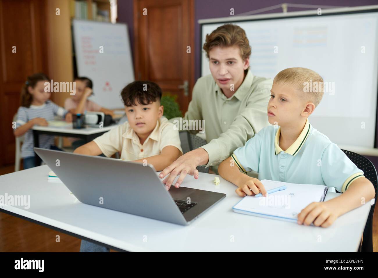 Educator Guiding Students in Classroom with Laptop Stock Photo - Alamy