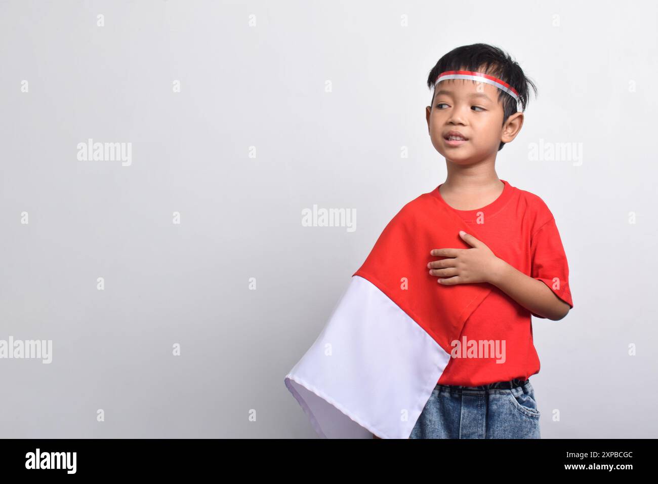 Asian boy smiling happily with Indonesian flag draped over his shoulder ...