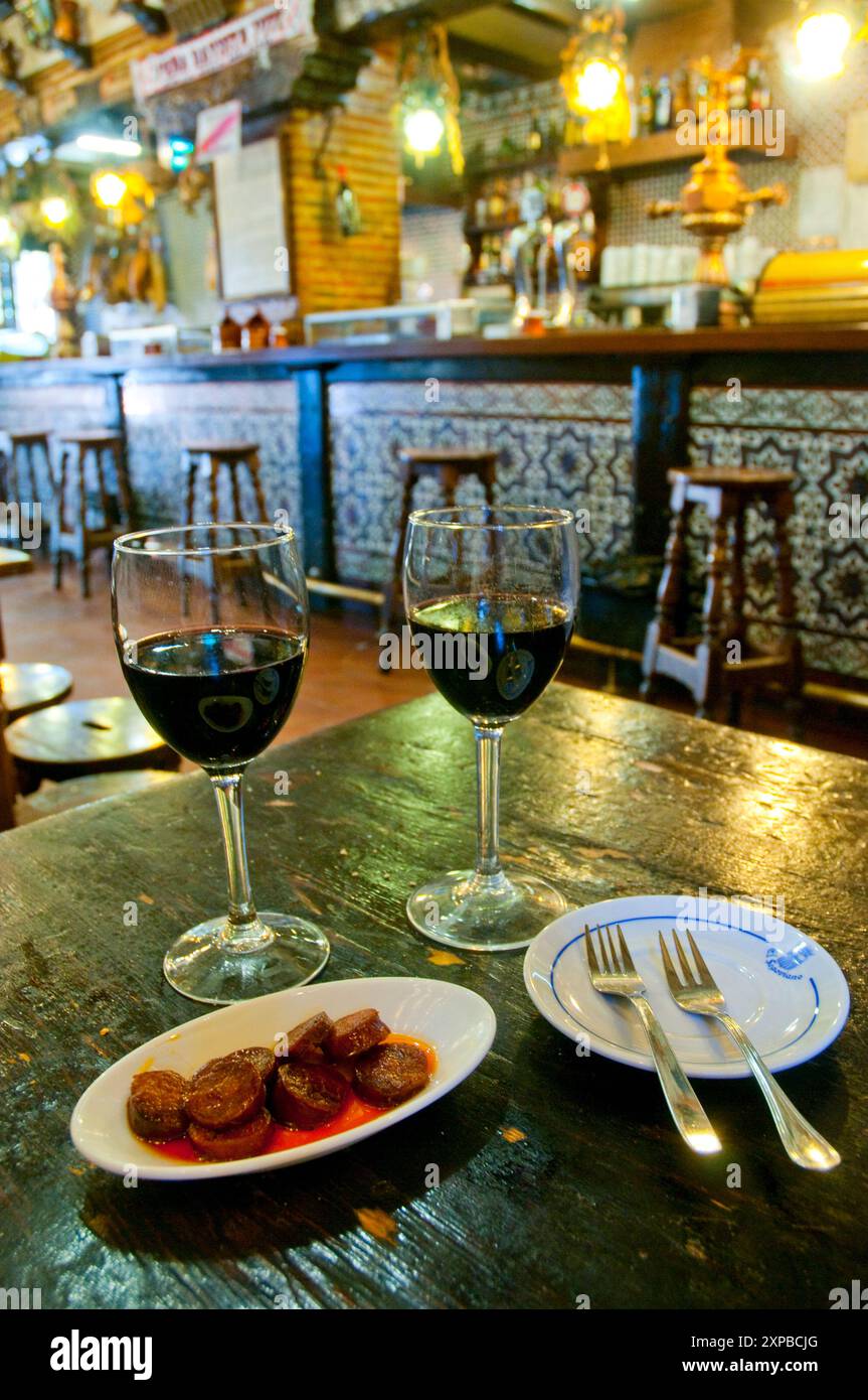 Fried chorizo with two glasses of red wine in a typical tavern. Spain ...