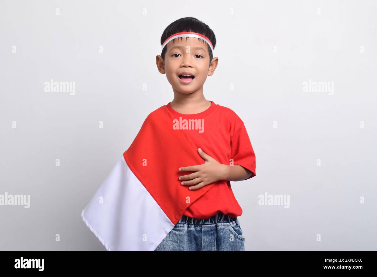 Asian boy smiling happily with Indonesian flag draped over his shoulder ...