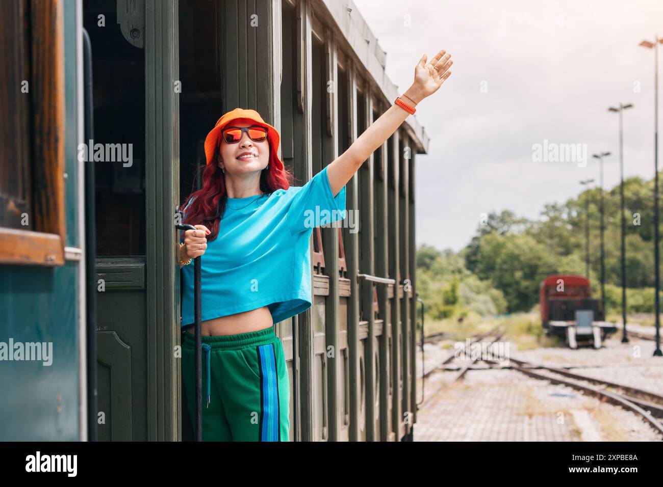 Retro train departing from station, a smiling woman tourist waving ...