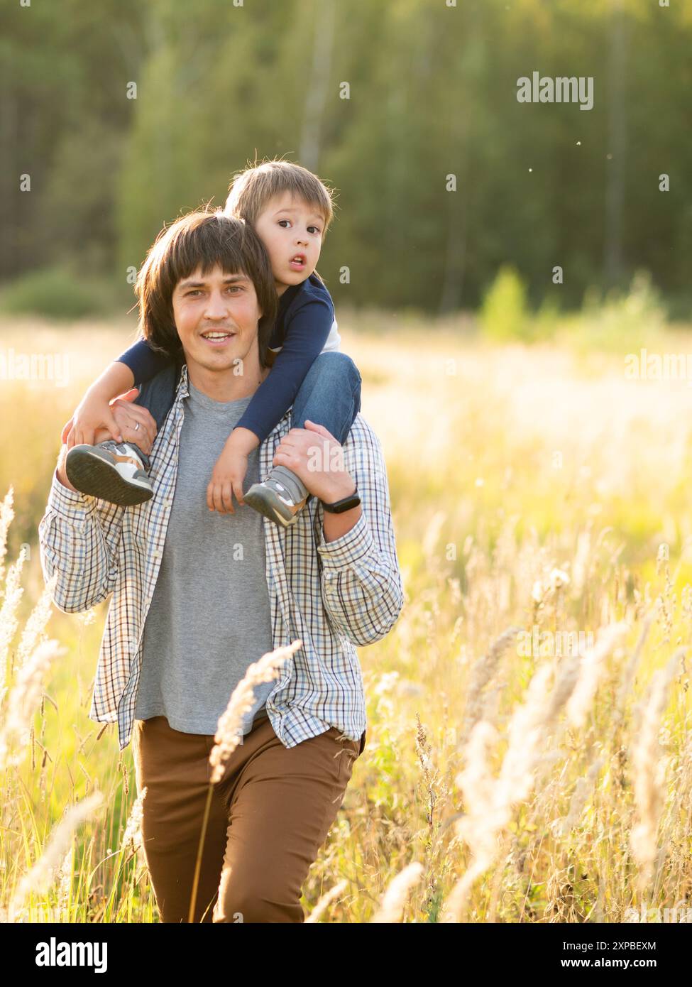 Father carries his son on shoulders. Family time outdoors. Man with ...