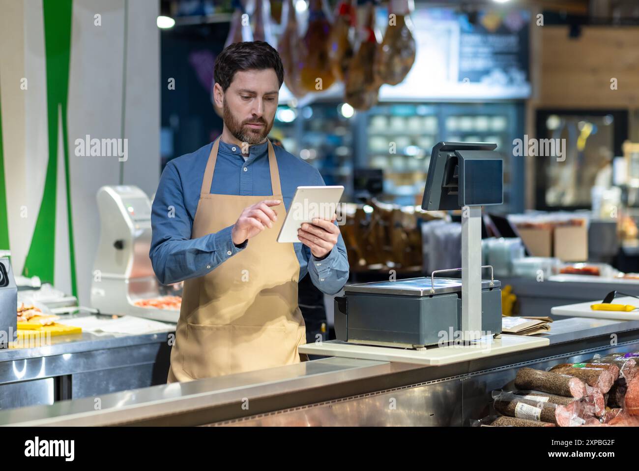 Male grocery store worker using tablet at checkout counter. Worker ...