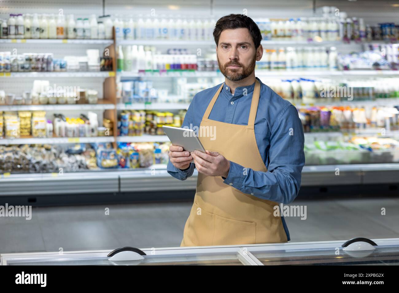 Male supermarket worker checking inventory using a digital tablet in ...