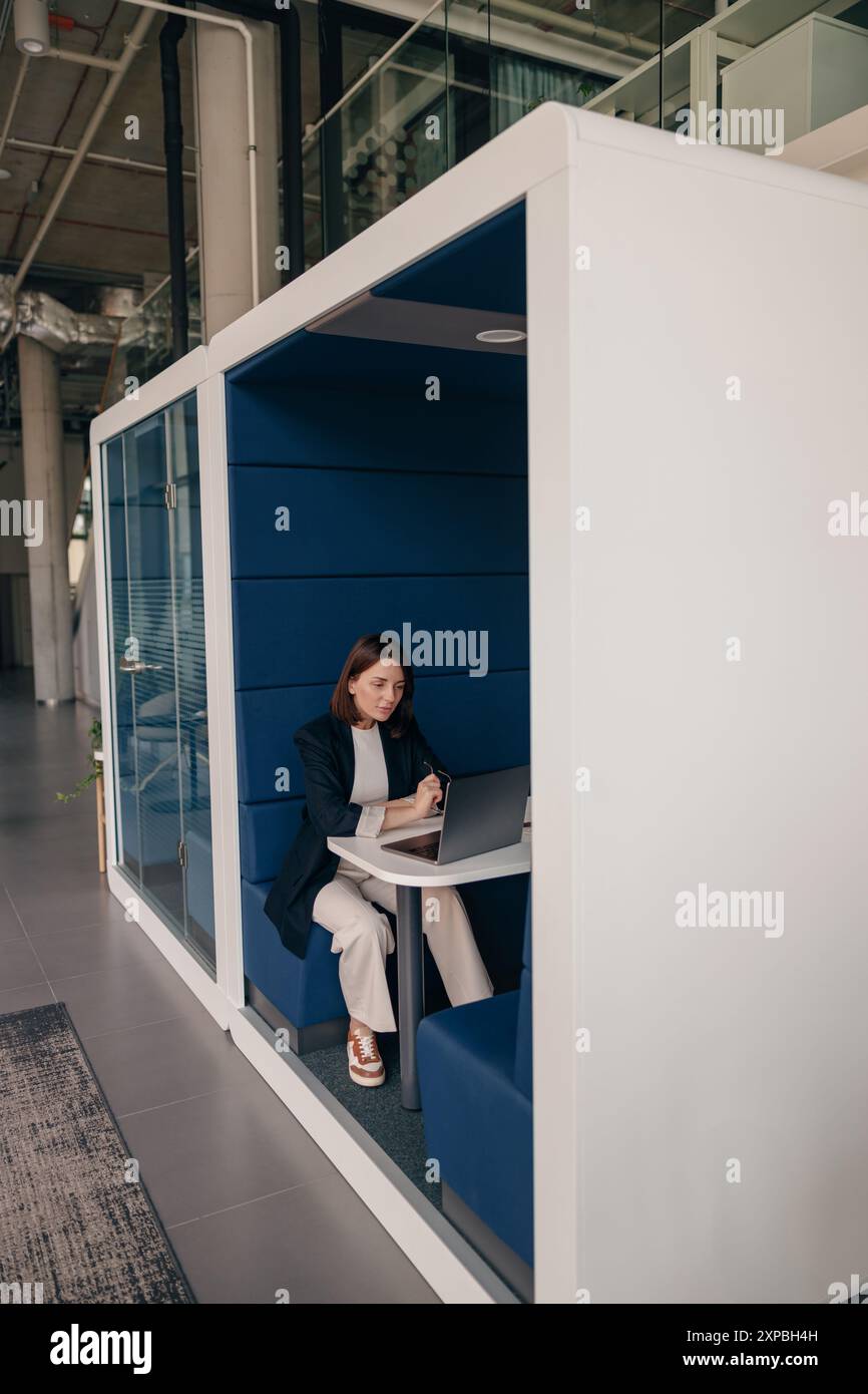 A professional businesswoman is working in a modern office booth for ...