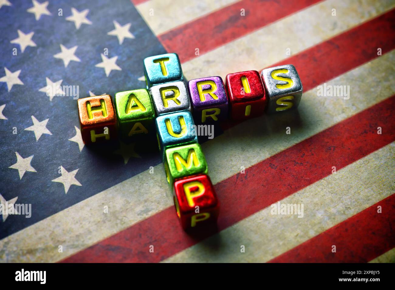 Würfelbuchstaben bilden die Schriftzüge Harris und Trump auf USA-Fahne ...