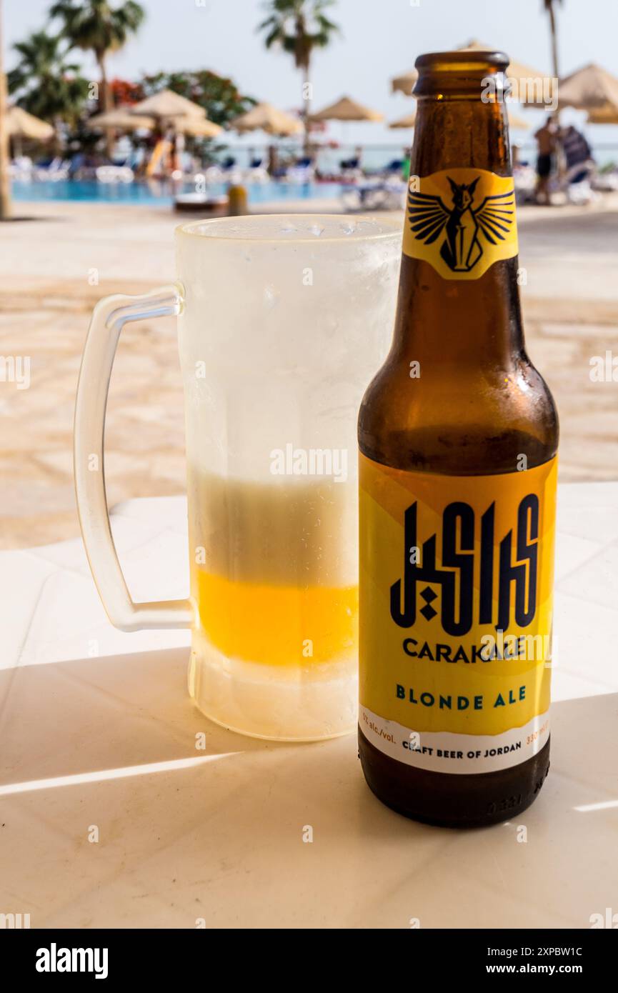 A bottle and frosted glass of Carakale Jordanian craft beer by the pool ...