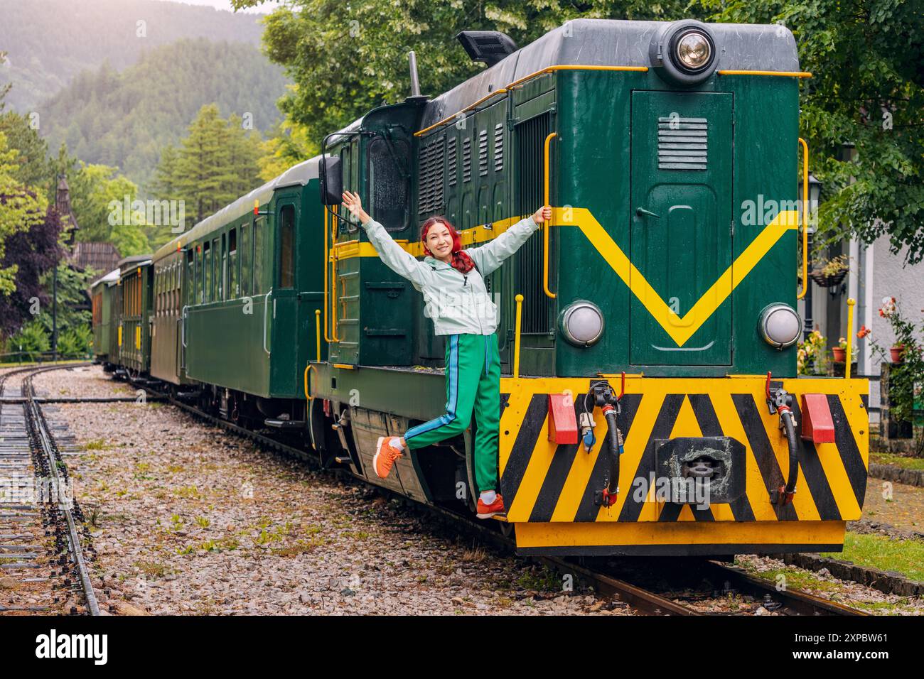 young woman waving goodbye from the vintage train, ready to embark on a ...