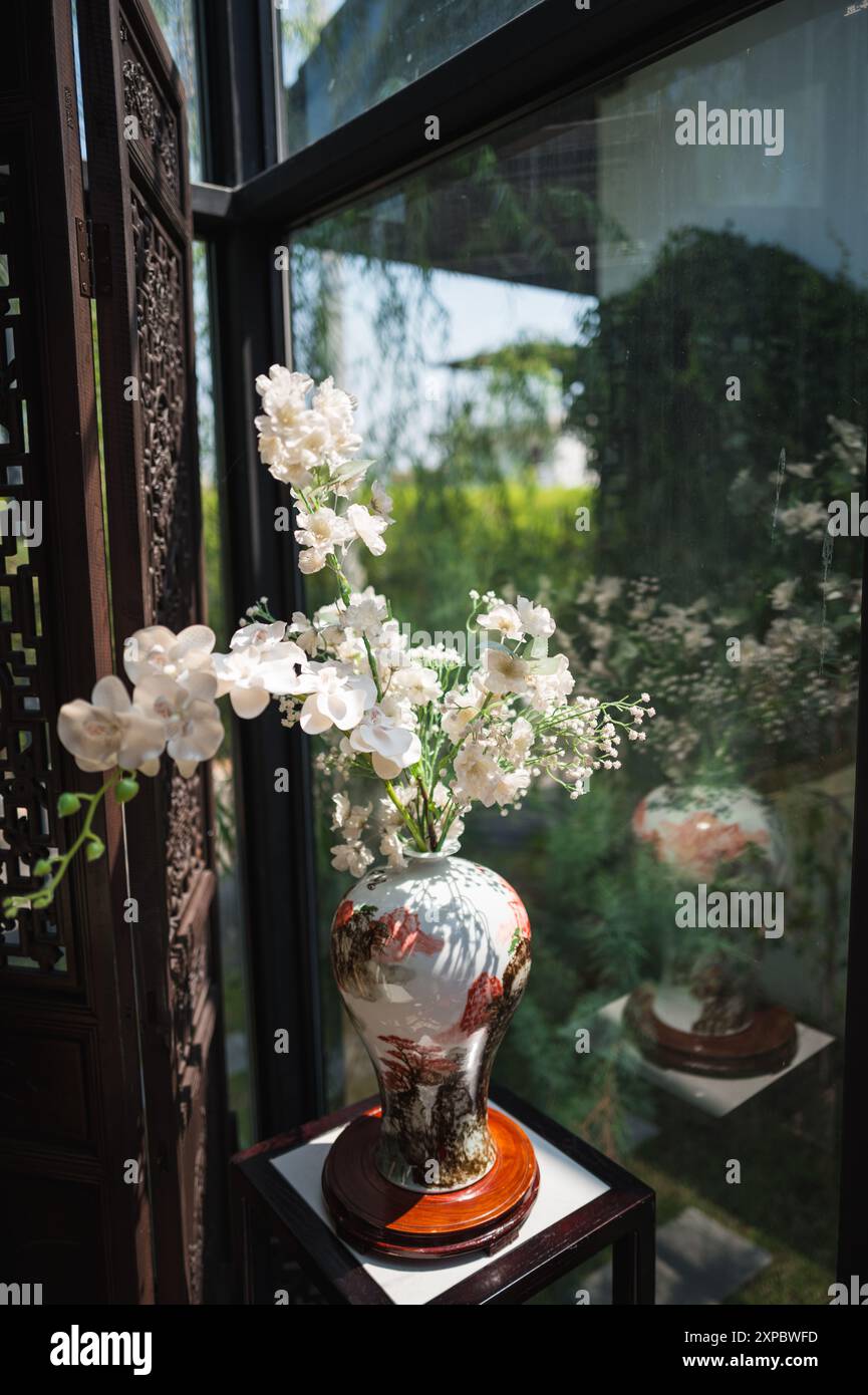 The ancient chinese style vase with artificial blooming white flowers ...
