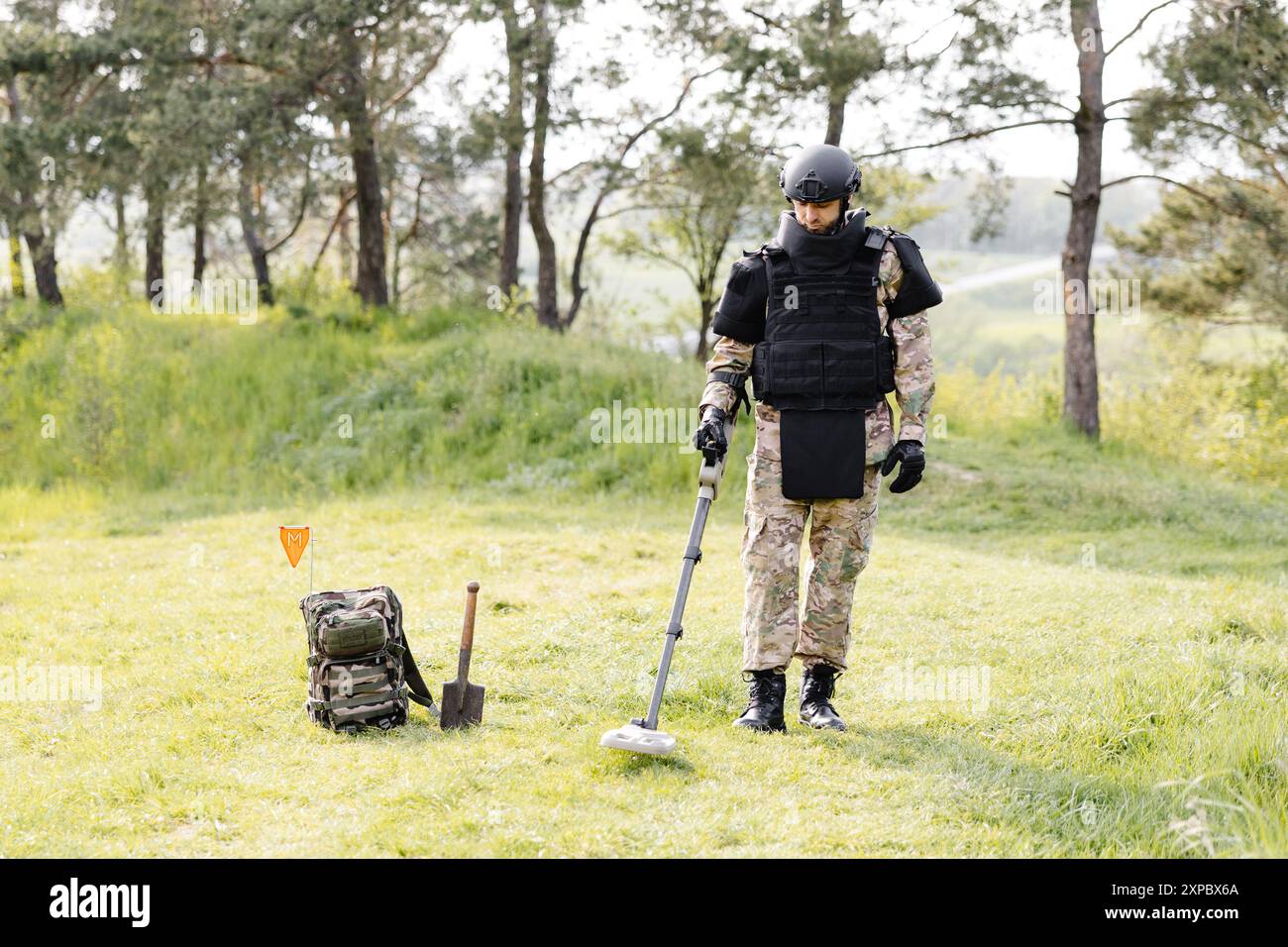 A man in a military uniform and bulletproof vest works in the forest ...