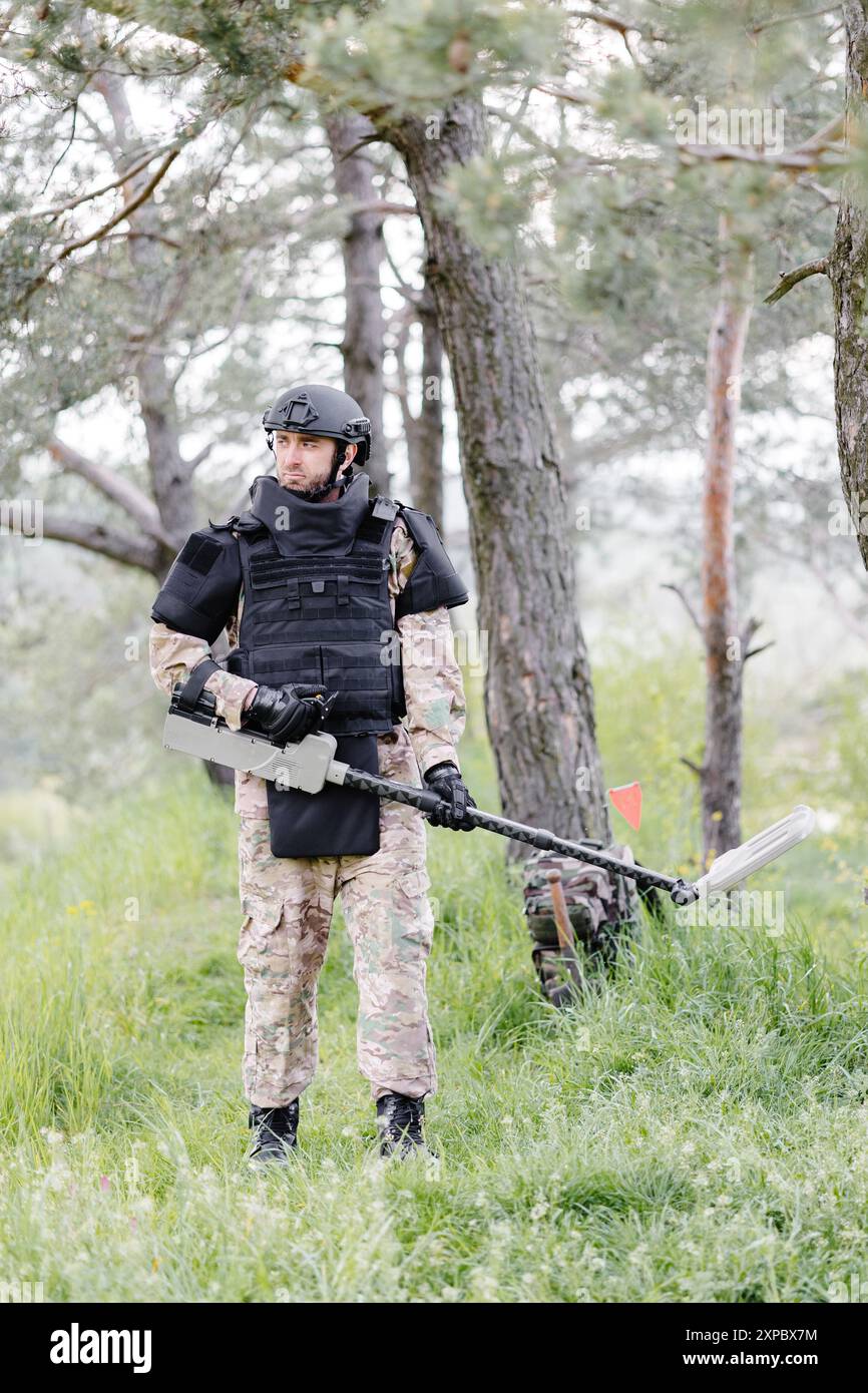 A man in a military uniform and bulletproof vest works in the forest ...