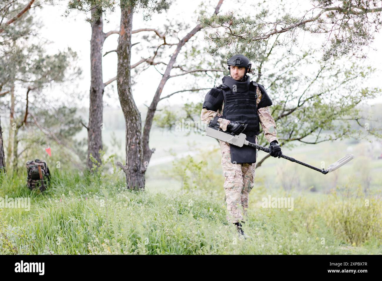 A man in a military uniform and bulletproof vest works in the forest ...