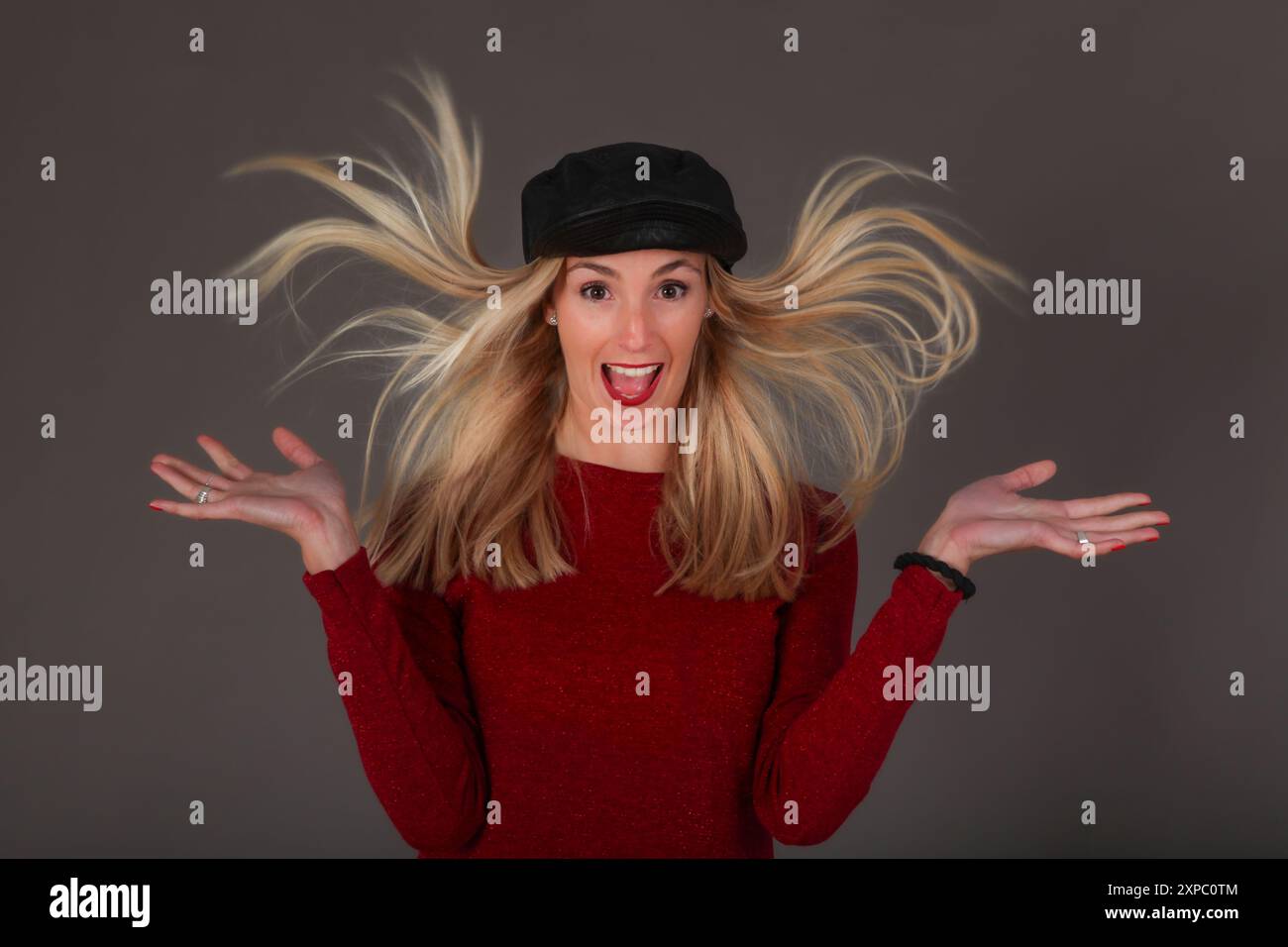 excited young woman with funny face expression and flying hair on dark ...