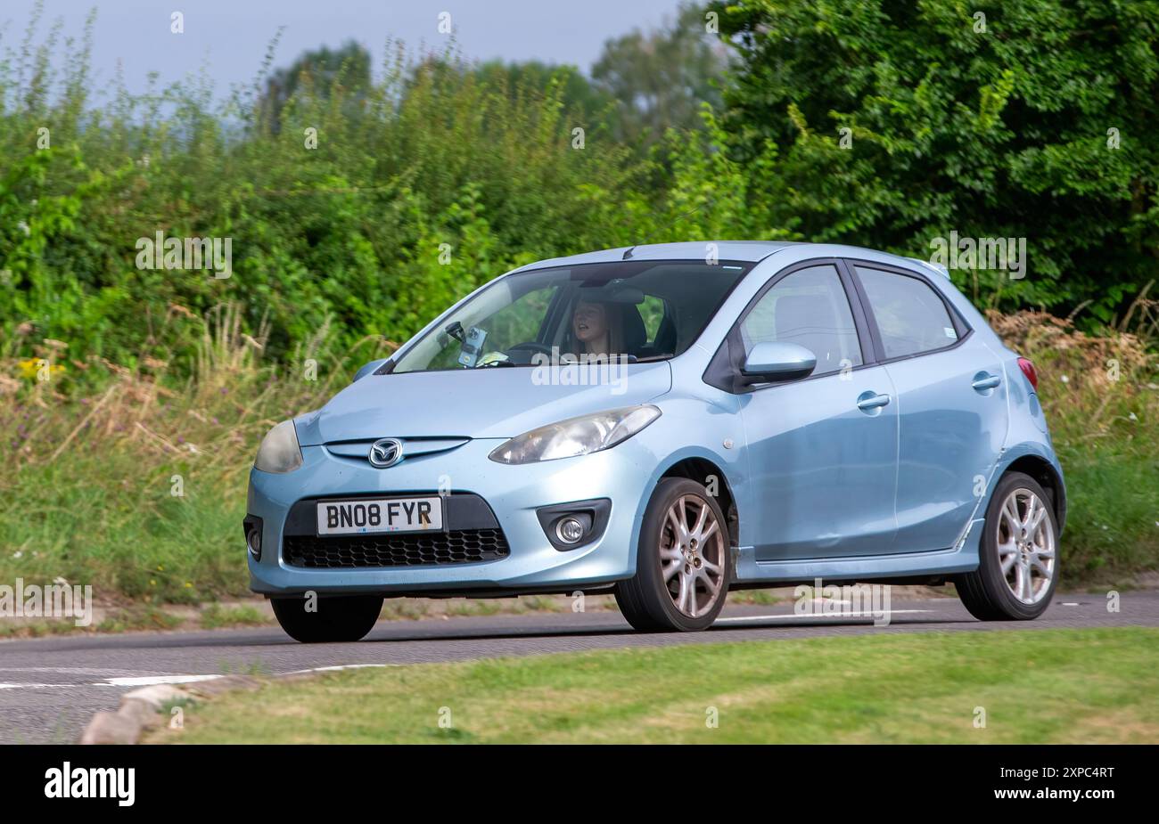 Whittlebury,Norhants,UK - Aug 4th 2024. 2008 blue Mazda 2 car driving on a British country road ...