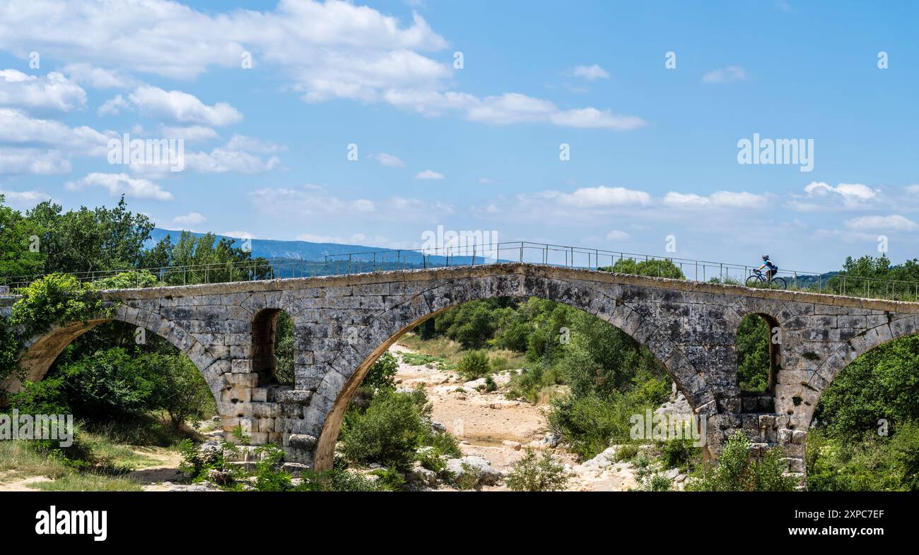 Female road cyclist crossing the 2000 year old Roman bridge, Pont ...