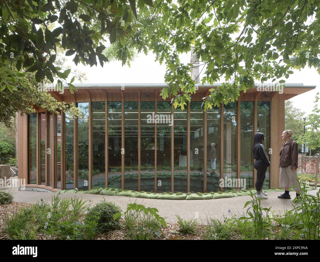 Curevd glass facade of new extension facing garden and trees. Rambert ...