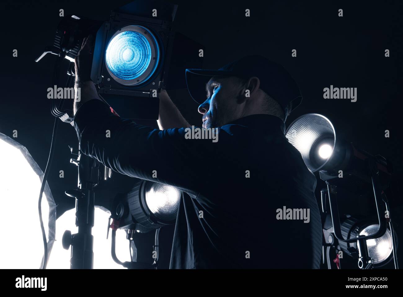 A technician focuses on positioning stage lights in preparation for a ...