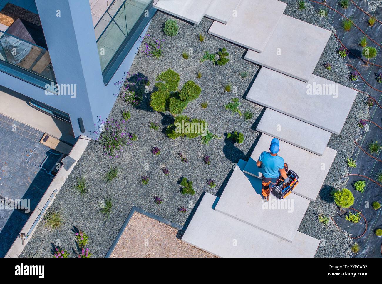 A landscaper is shaping a garden pathway with a landscaping tool ...