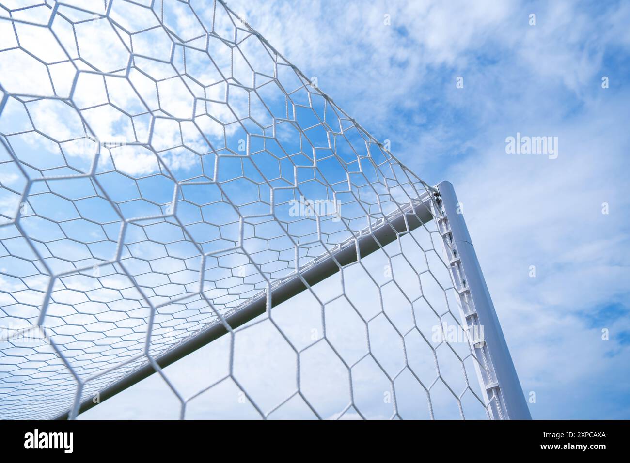 A close-up of a white soccer goal net with a vibrant blue sky in the ...