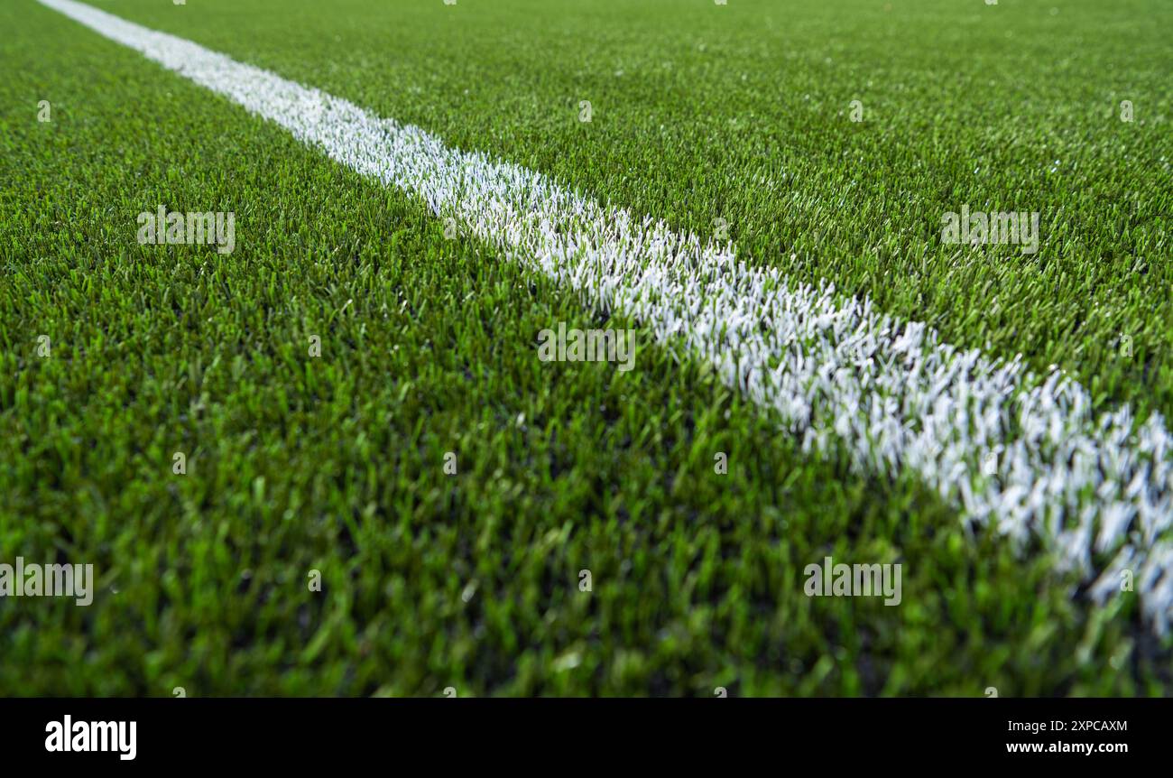 A vibrant green sports field features a crisp white line marking the ...